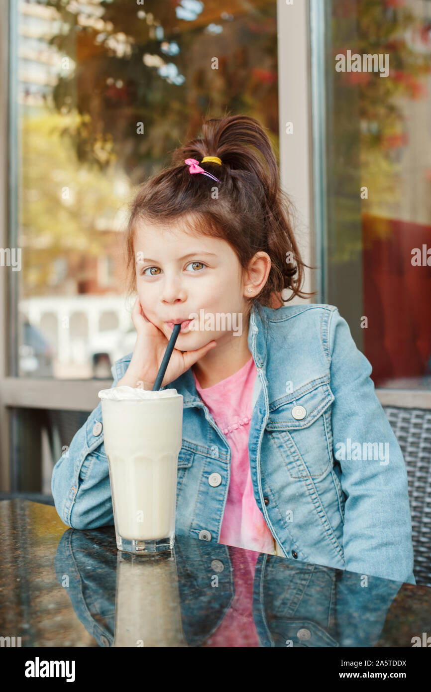 Funny smiling Caucasian preschool girl drinking milk shake with paper ...
