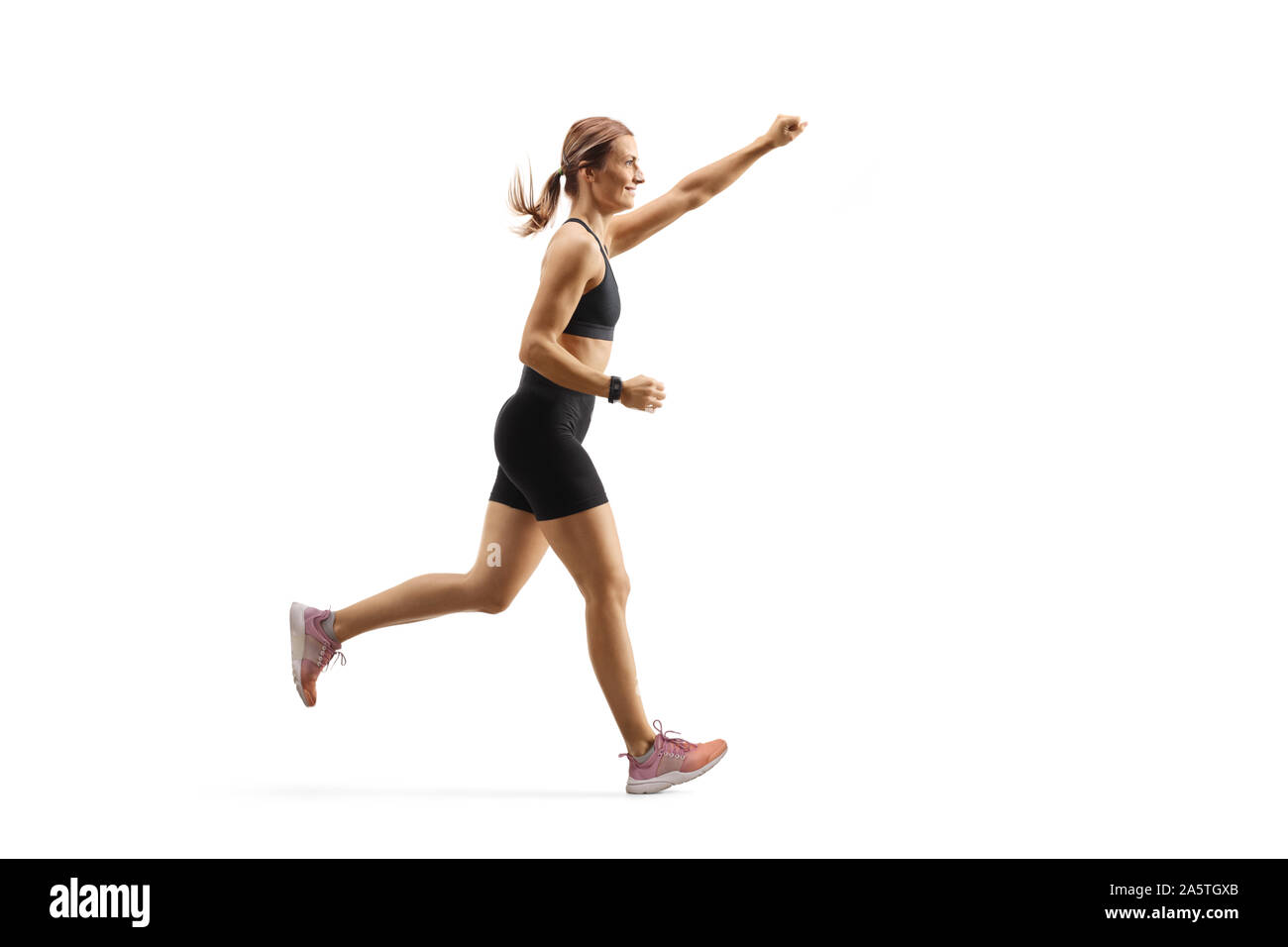 Full length profile shot of a fit young woman running with raised arm ...