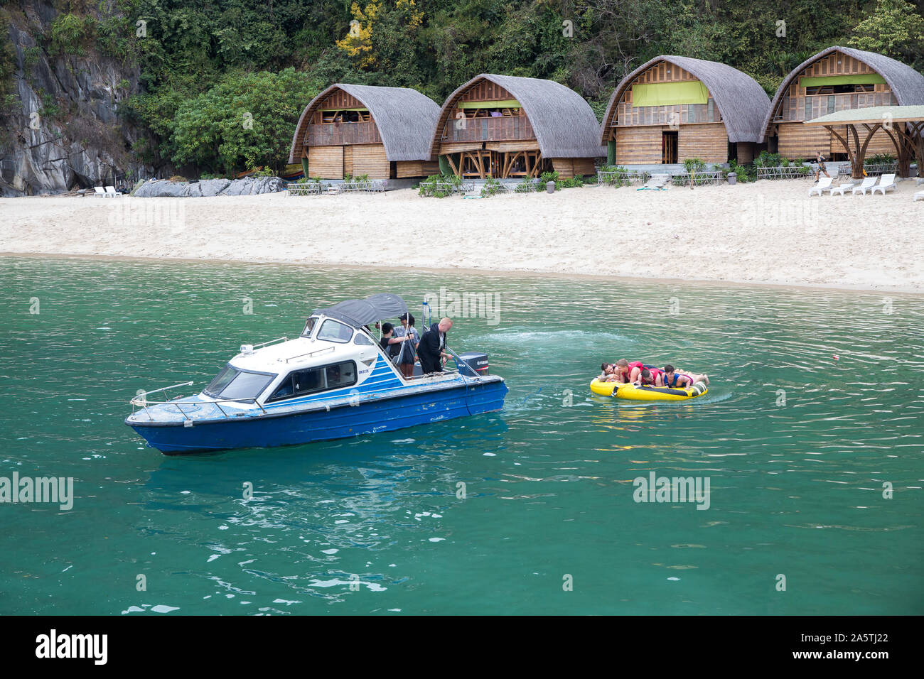 A boat prepares to tow people on an inner tube in Halong Bay Stock ...