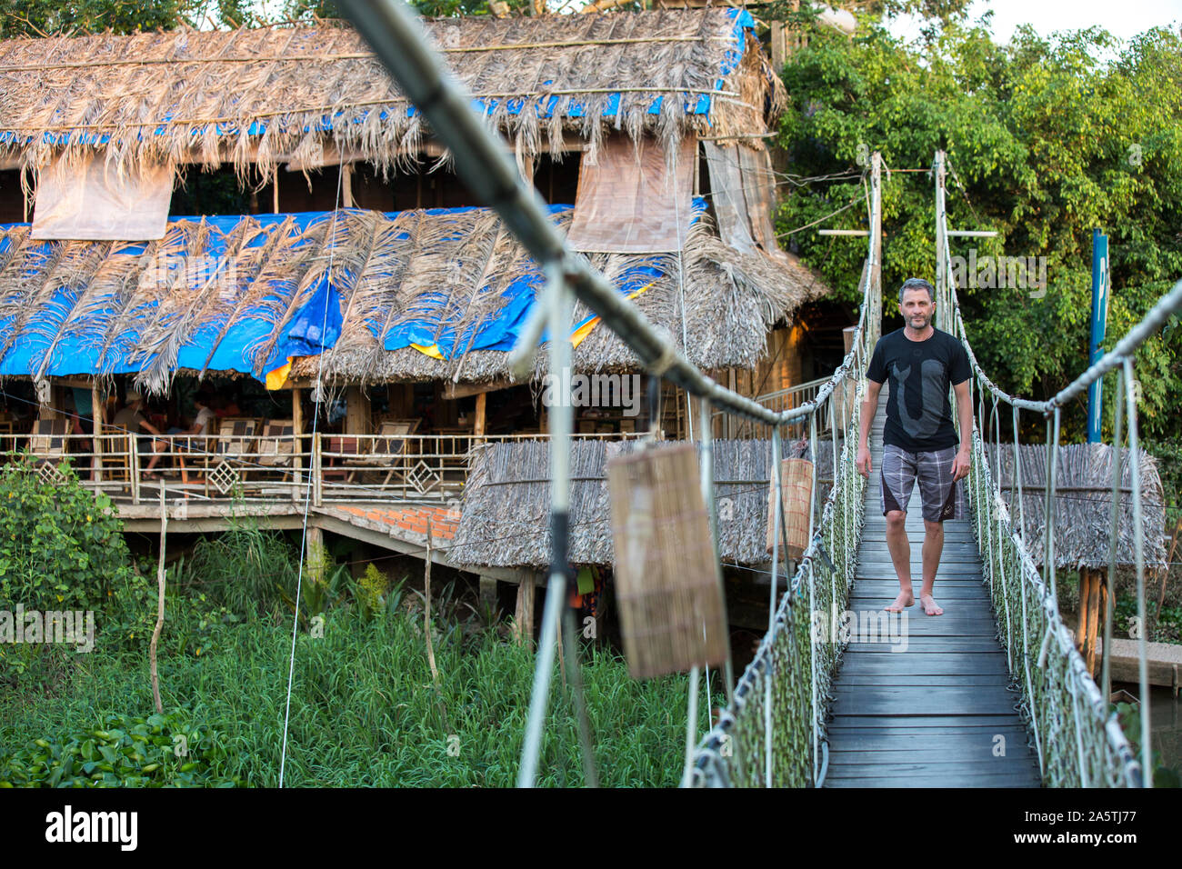 A man walk on a suspension bridge in rustic setting Stock Photo - Alamy