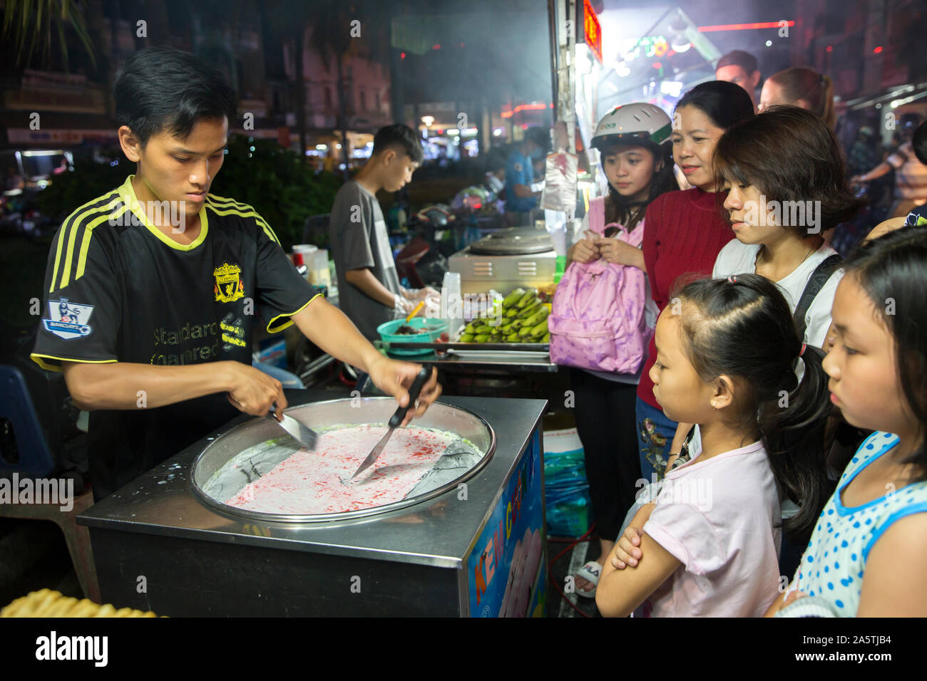 A crowd watches a man makes rolled ice-cream in Vietnam Stock Photo - Alamy