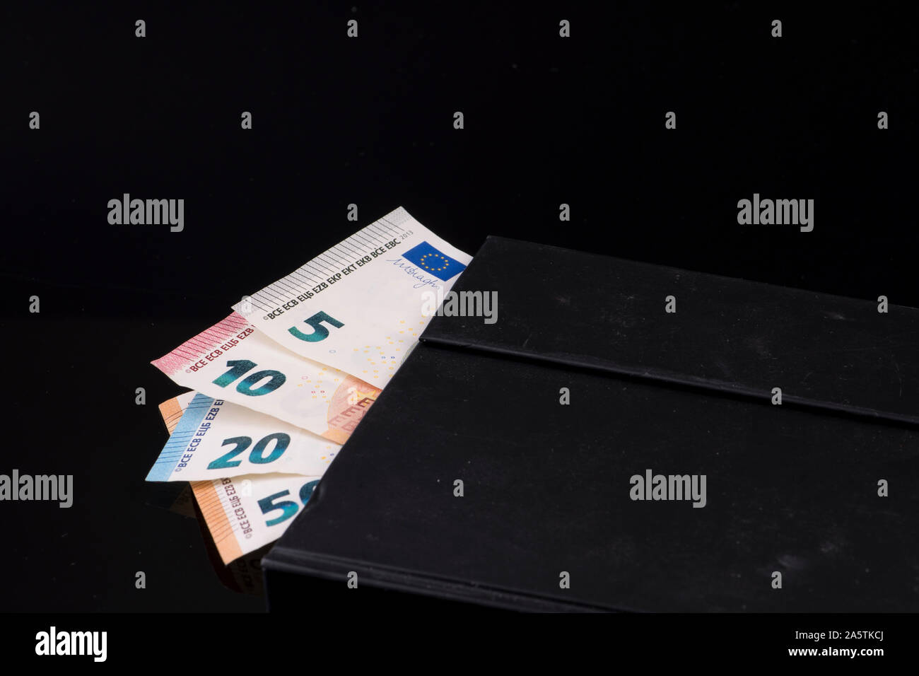 Black book with banknotes on black background Stock Photo - Alamy