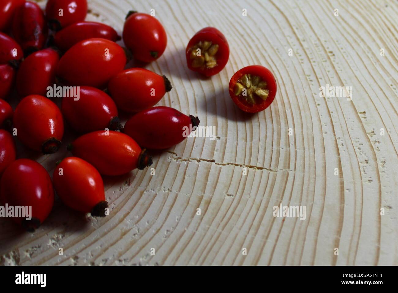 The picture shows rose hips on wooden ground Stock Photo - Alamy