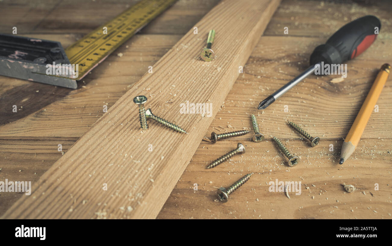Screws, screwdriver, ruler and a pencil on a wood table. Concept tools ...