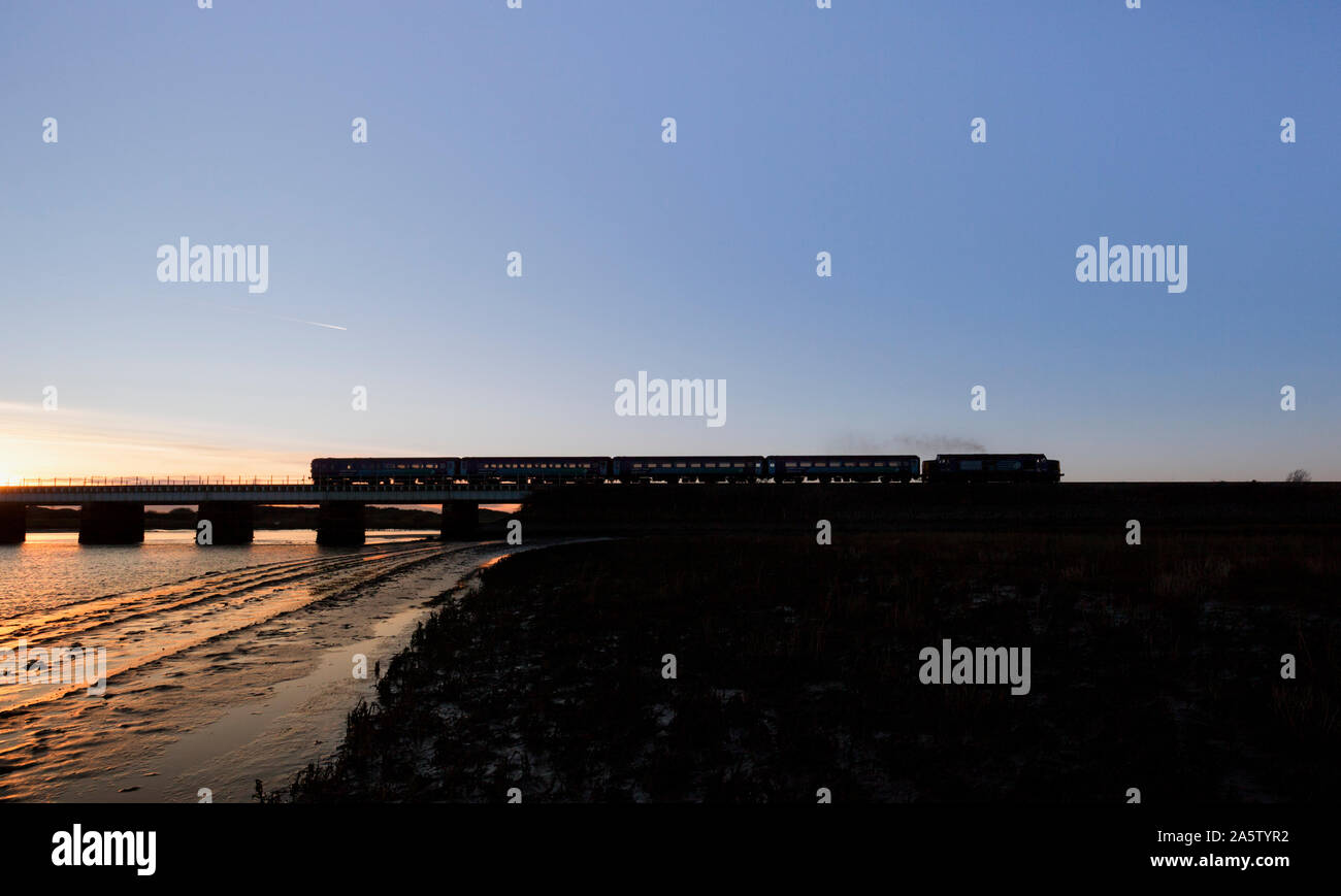 Silhouette of a DRS class 37 locomotive hauling a Arriva Northern rail ...