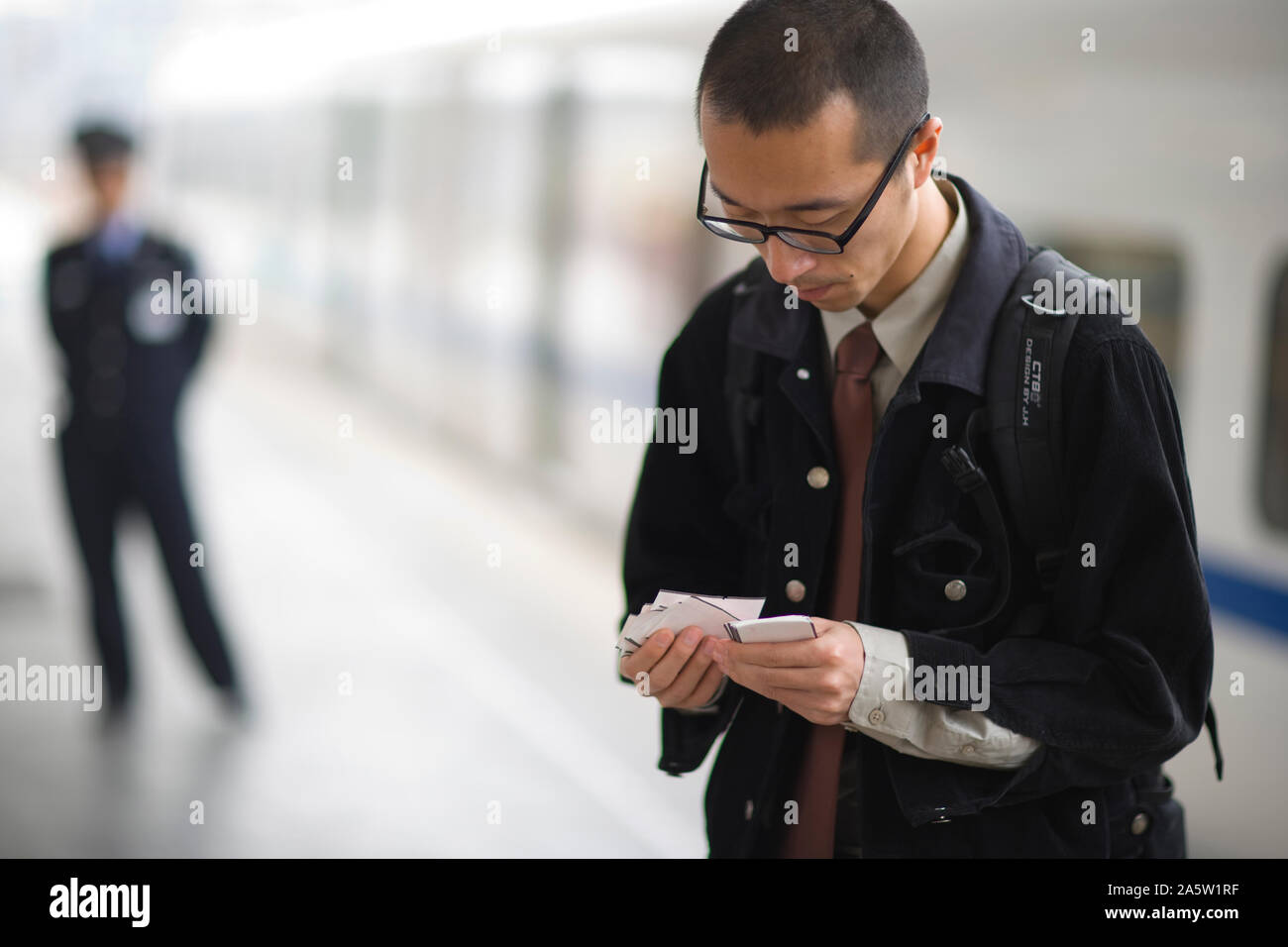 Young adult businessman looking through tickets on a train platform ...