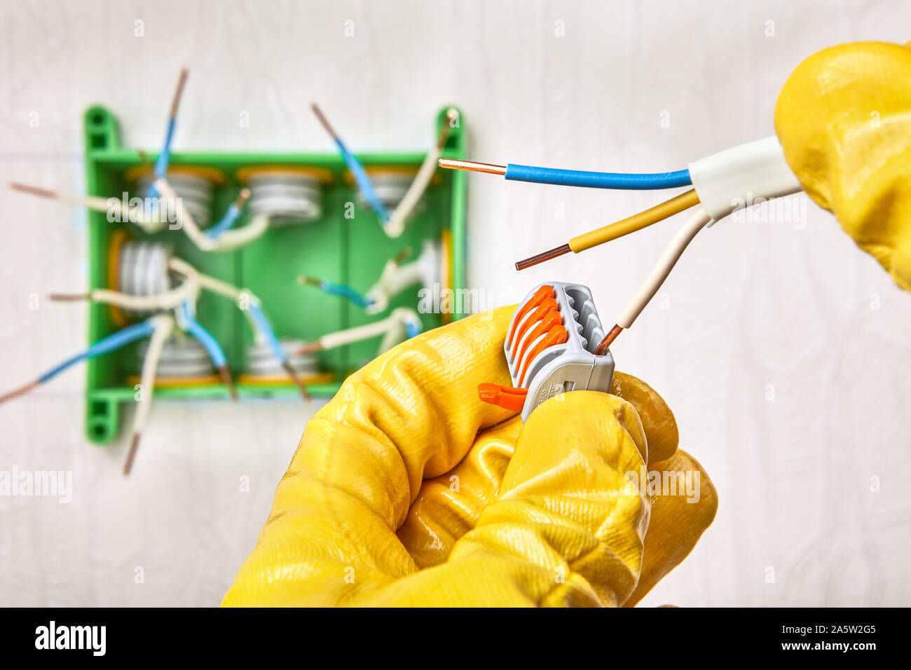 A technician connects copper wires using a connector or terminal block ...