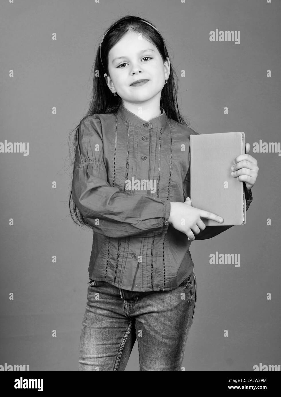 Published information. Small child holding book with orange cover for ...