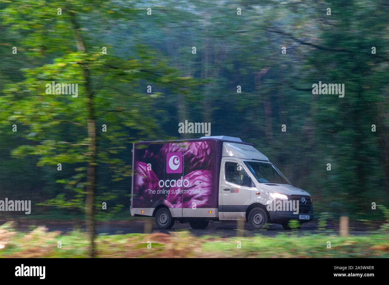An Ocado Mercedes Benz box van drives along a narrow country lane in ...
