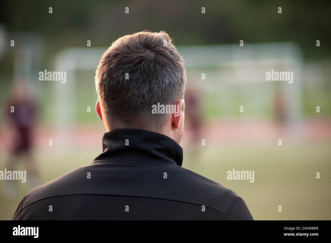 Young football, soccer coach watches the team during the game, rear ...
