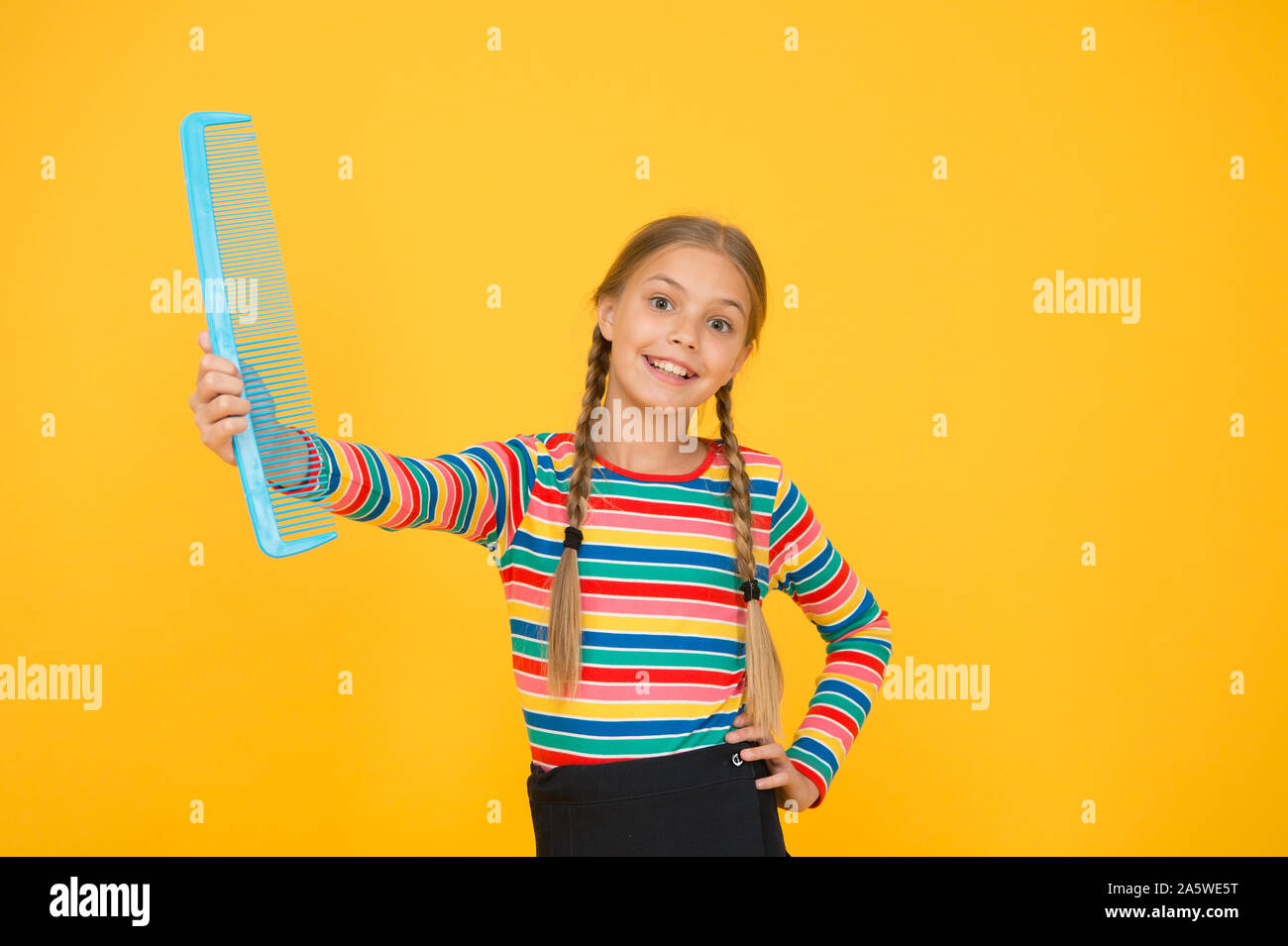 Comb not just for blonde. Happy child hold blue comb yellow background ...