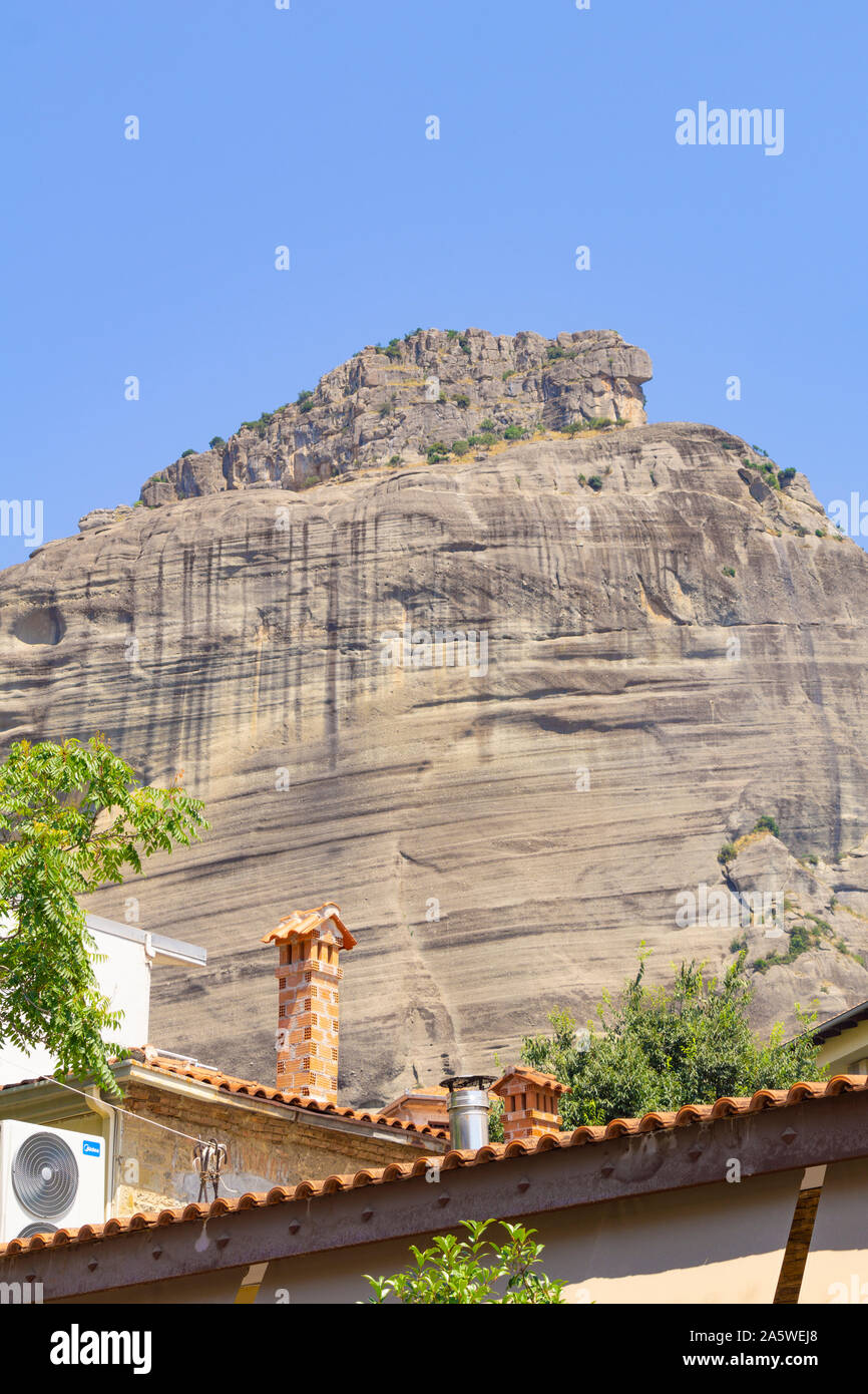 Huge rock formation rises above houses with terracotta tiles and ...