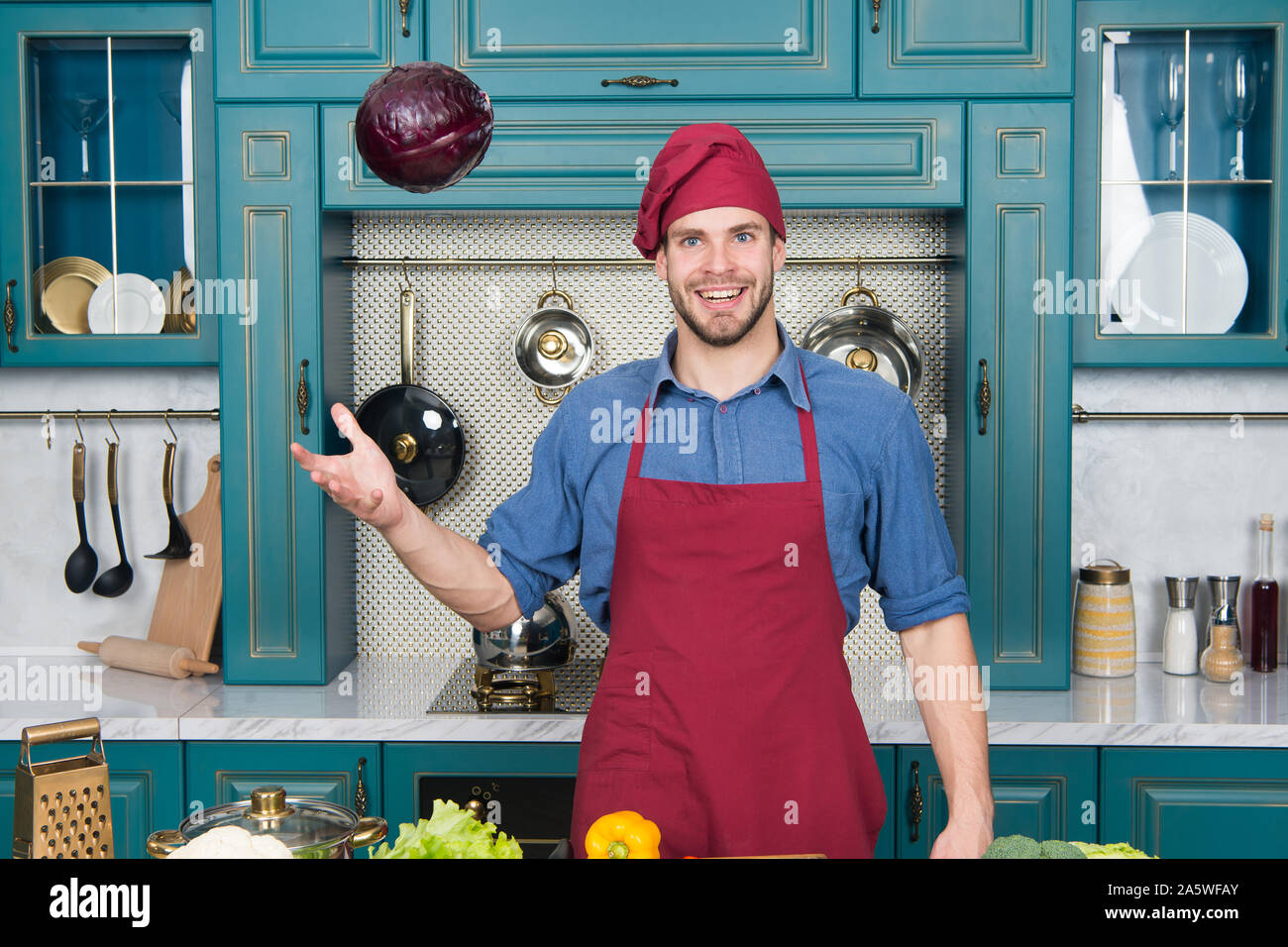 Catch it. Handsome cook in kitchen. Chef following recipe. Cooking ...