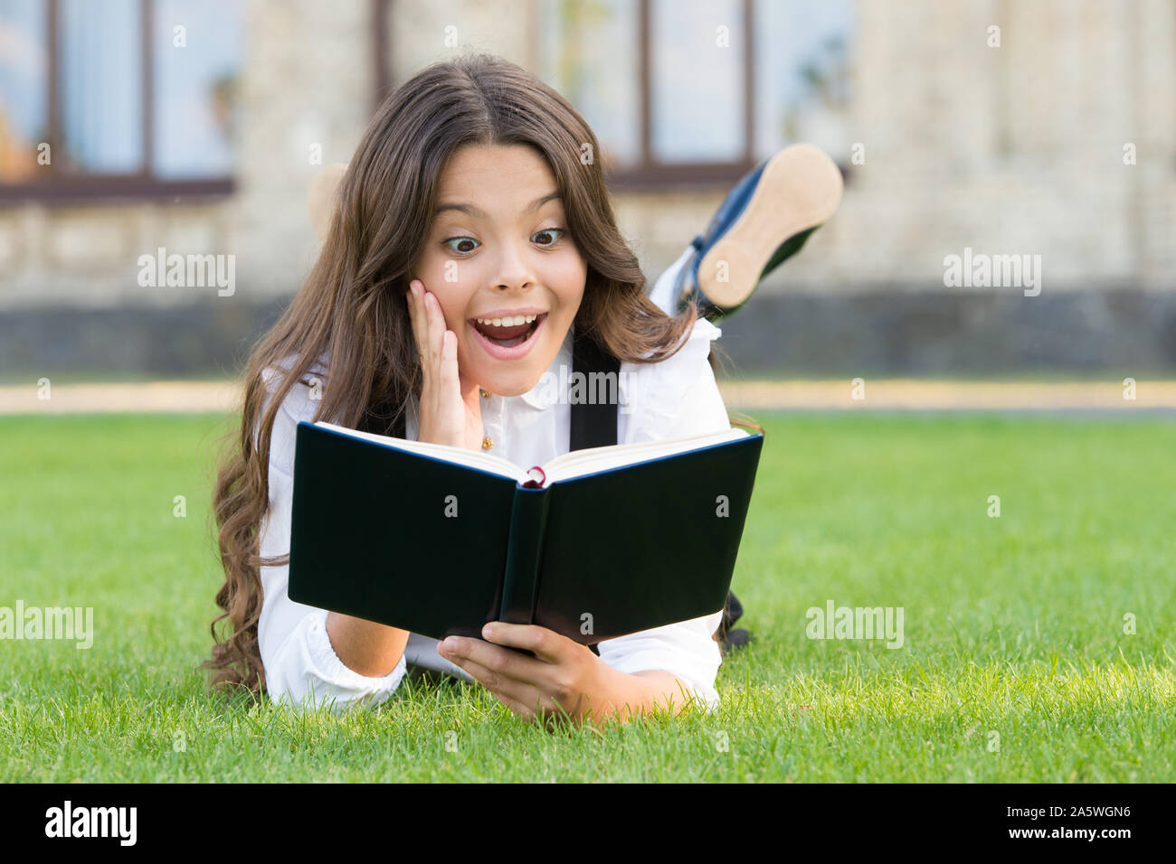 Book with unexpected surprise. Surprised child read book on green grass ...