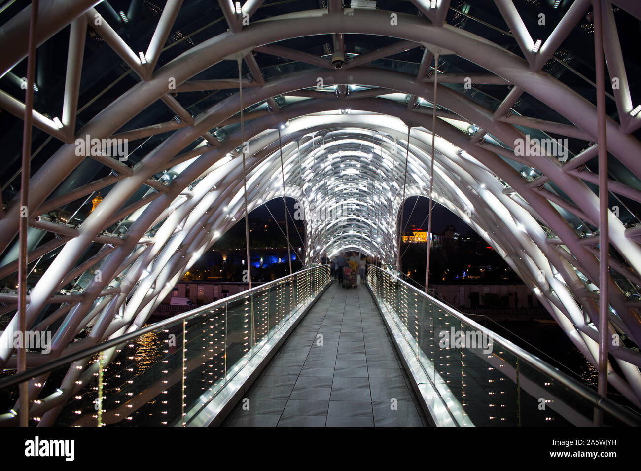 Pedestrian bridge. Steel glass construction illuminated numerous lights ...