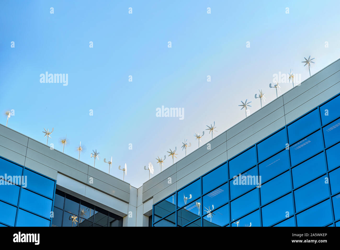 Wind turbines producing energy on top of modern office building on a ...