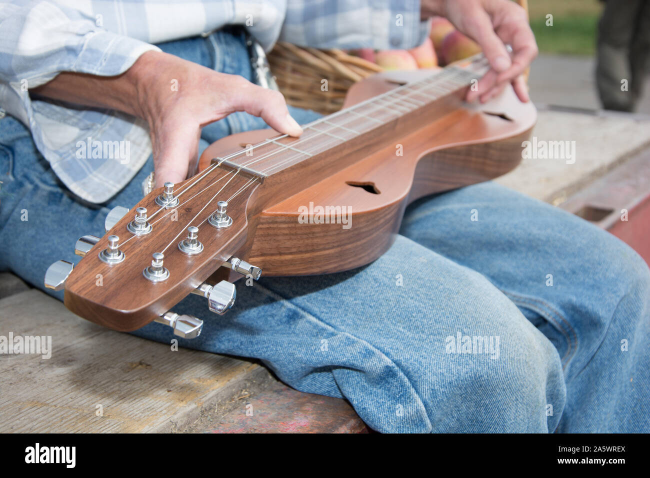 A woman in western attire learns to play the dulcimer on the bed of a ...
