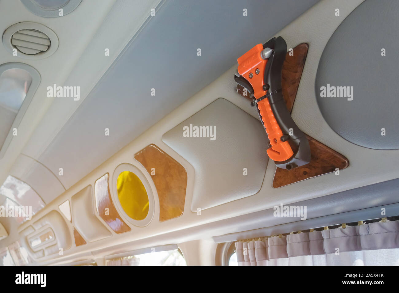 Orange safety glass hammer mounting near the window glass and curtain ...