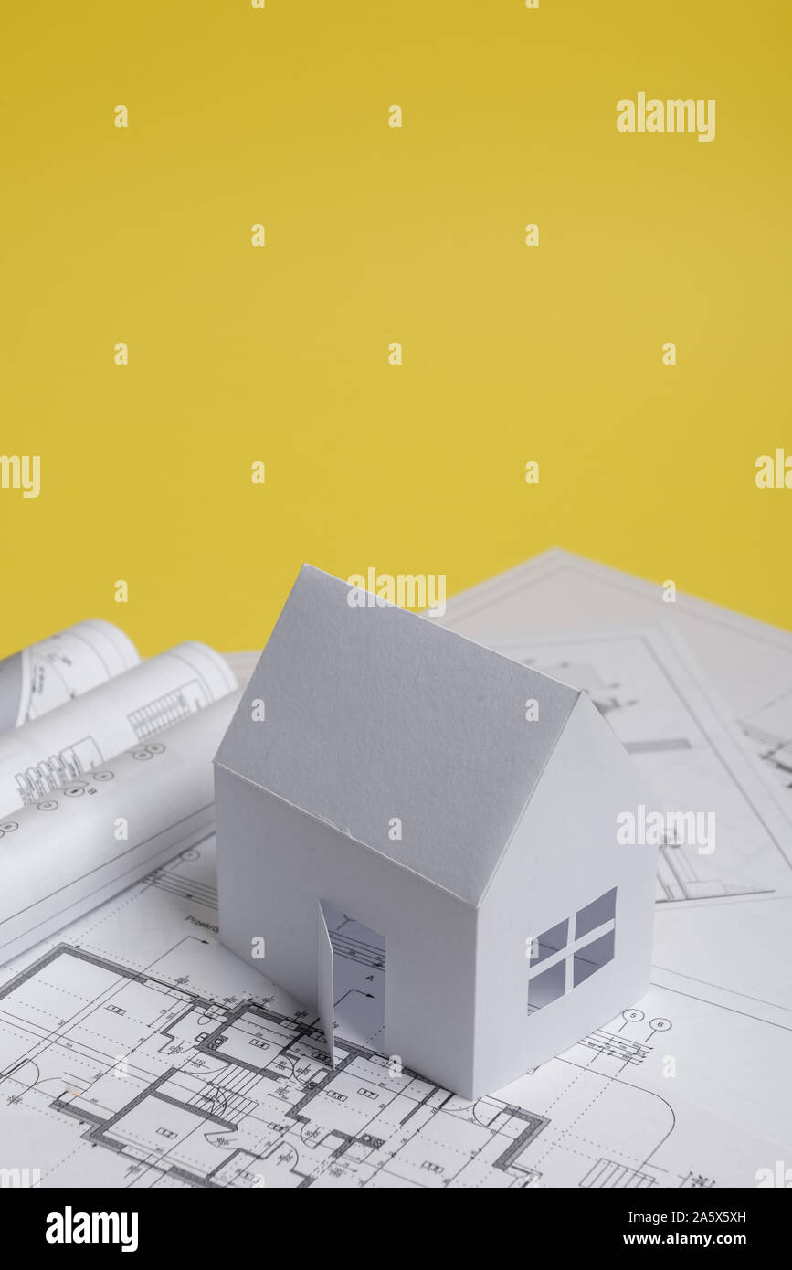 White family paper house, house projects plan and blueprints on yellow ...