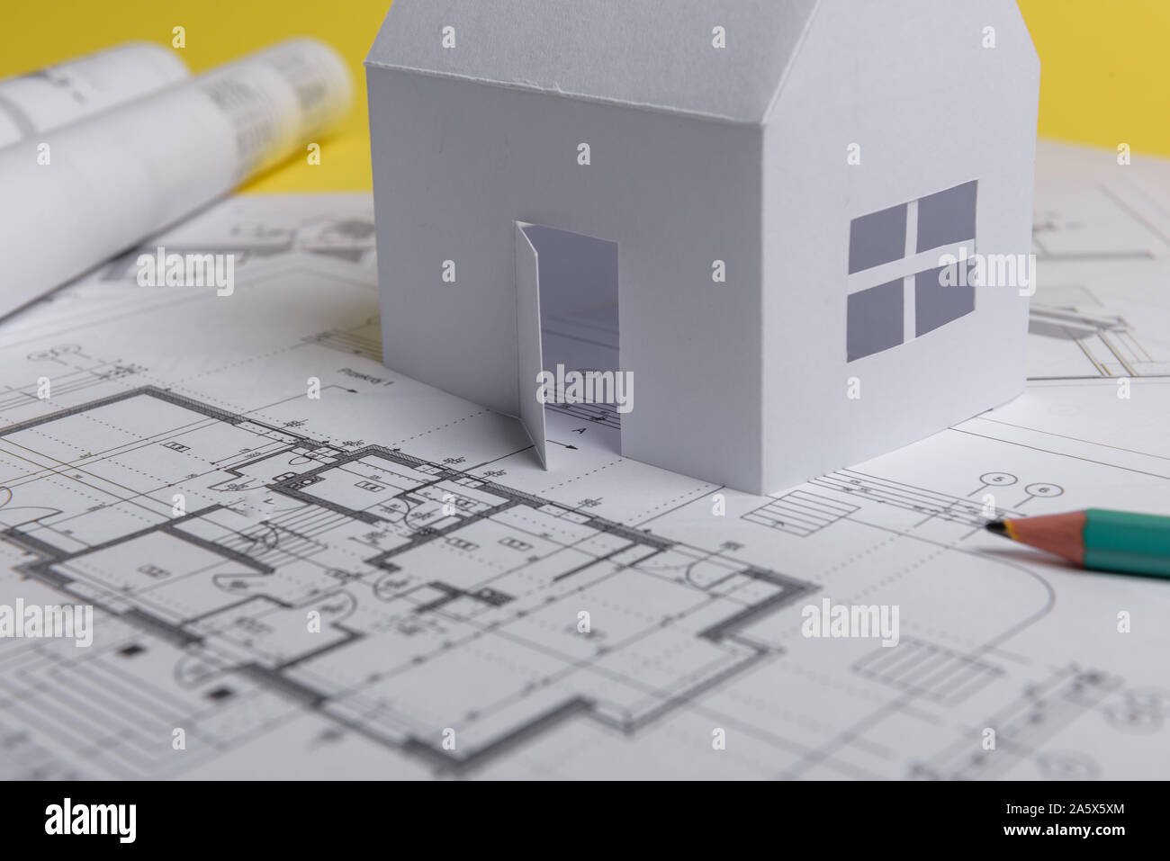 White family paper house, house projects plan and blueprints on yellow ...