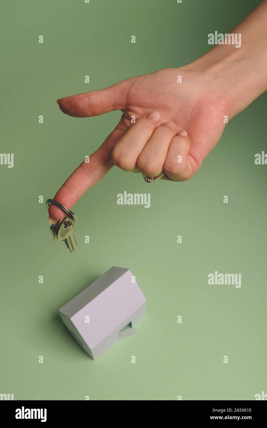 White family paper house. House keys in hand on mint background paper ...