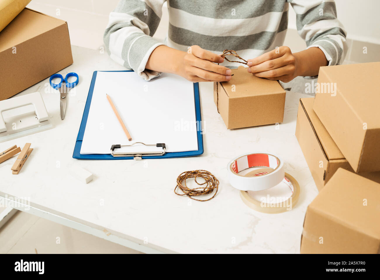 Woman packing cardboard boxes using tape dispenser Stock Photo - Alamy