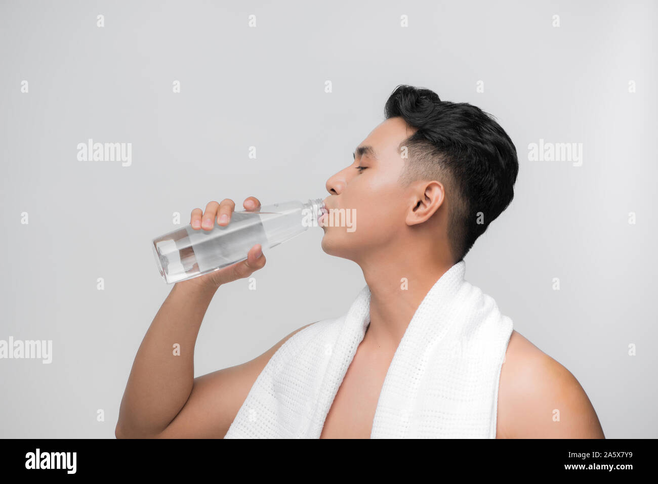 young handsome fit man drinks water / male model with bottle of water ...