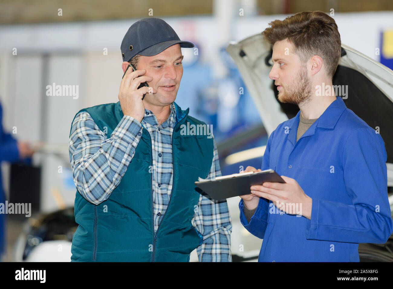 car mechanic and apprentice checking a car engine Stock Photo - Alamy