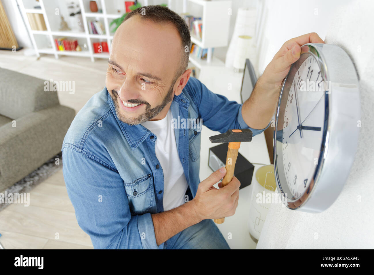 repairman hanging a clock on the wall Stock Photo - Alamy