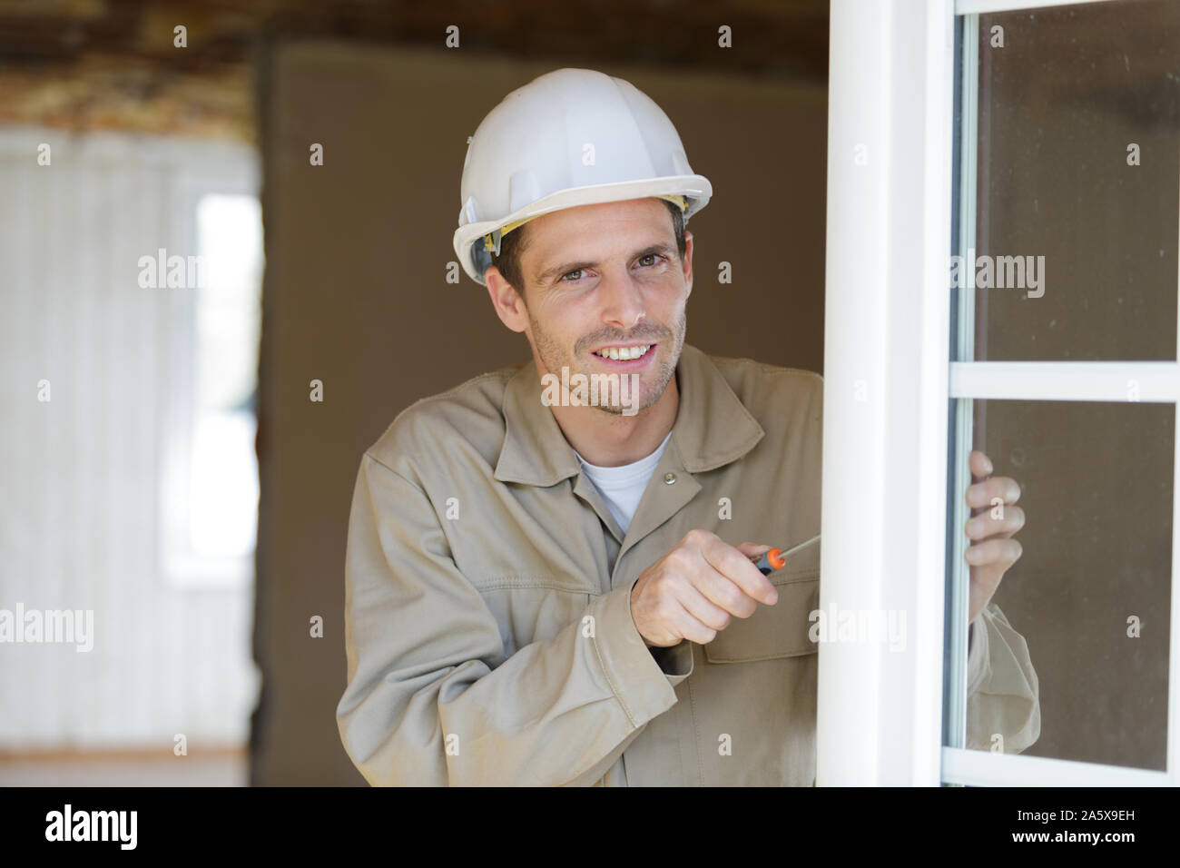 male glazier installing window with screwdriver Stock Photo - Alamy