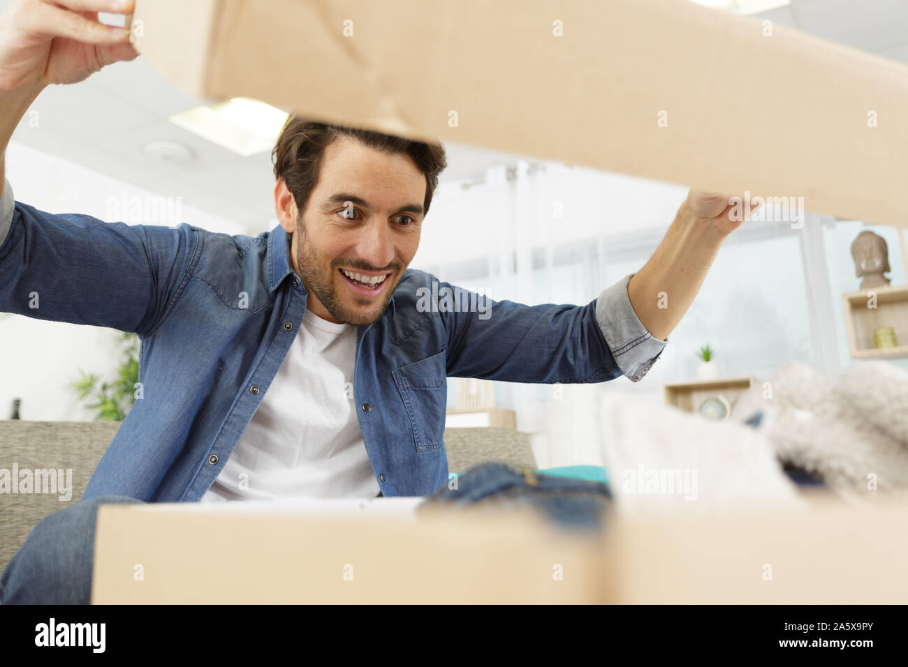 surprised happy man unboxing a gift box Stock Photo - Alamy