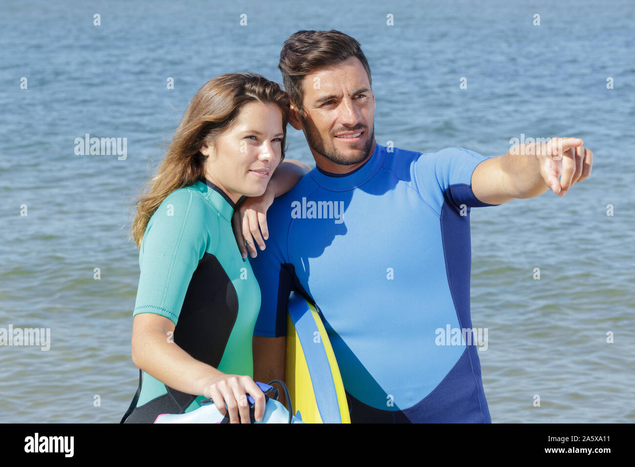 surfing couple pointing at something Stock Photo - Alamy