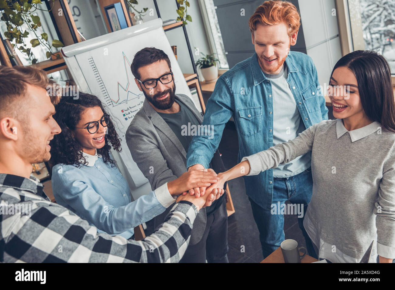 Startupers working at office together standing holding hands top view ...