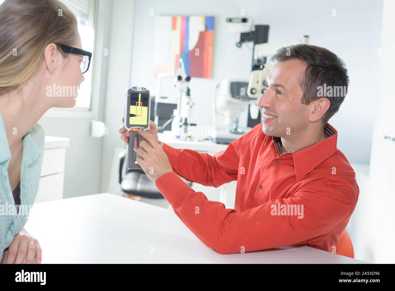optician showing patient results of eye test on handheld device Stock ...