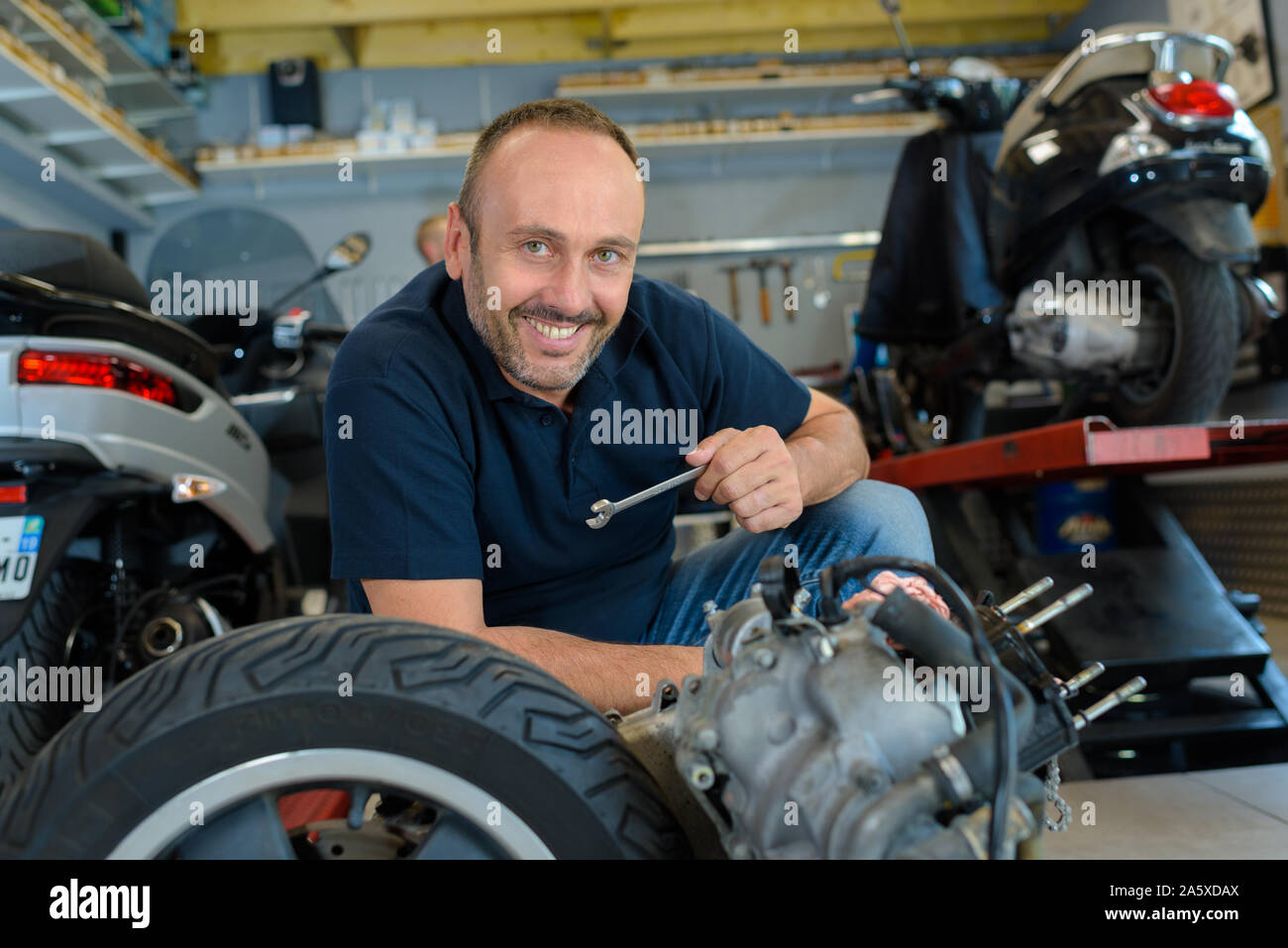 man fixing motorcycle in garage Stock Photo - Alamy