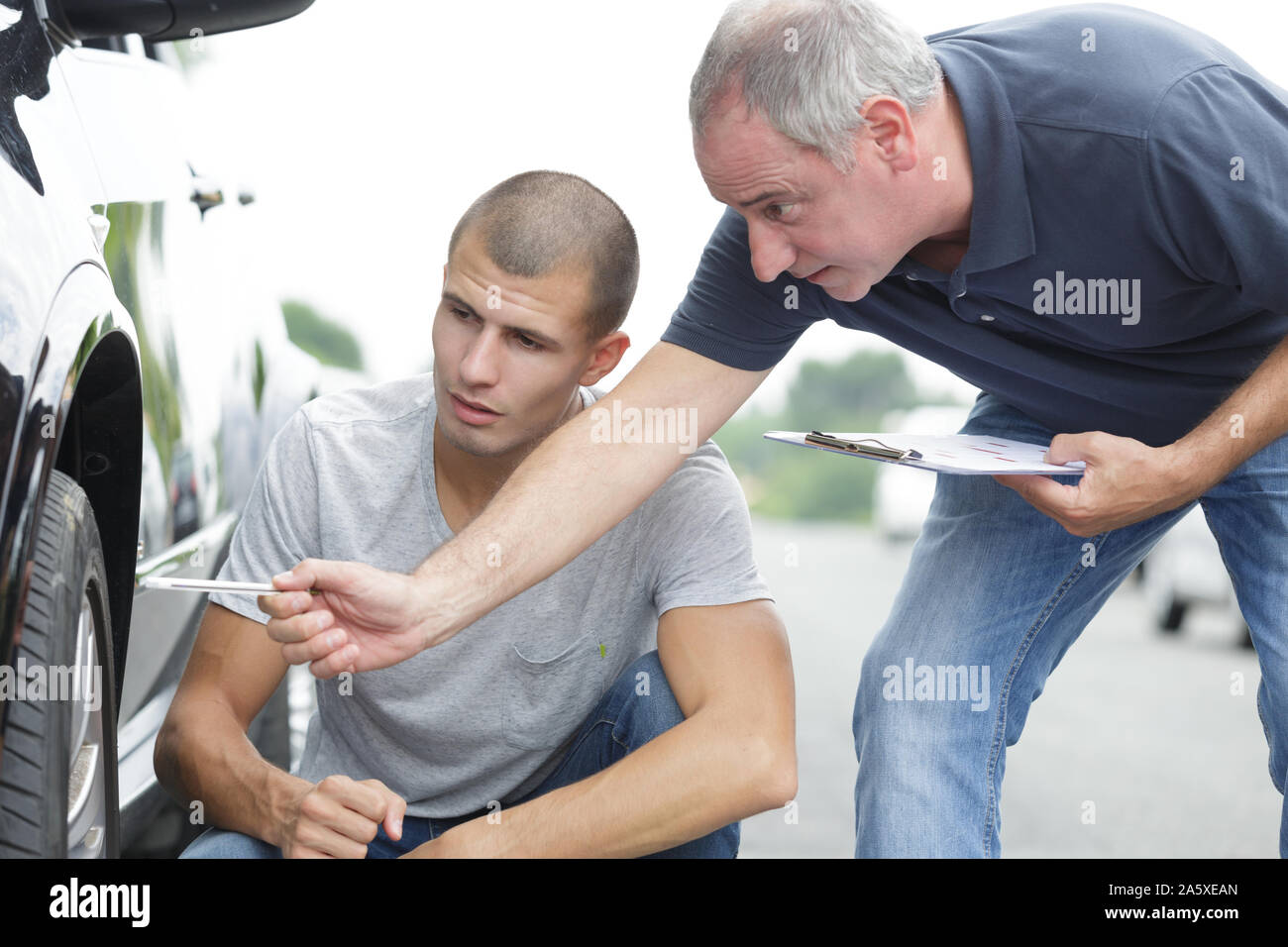 mechanic with clipboard showing wheel at customer Stock Photo - Alamy
