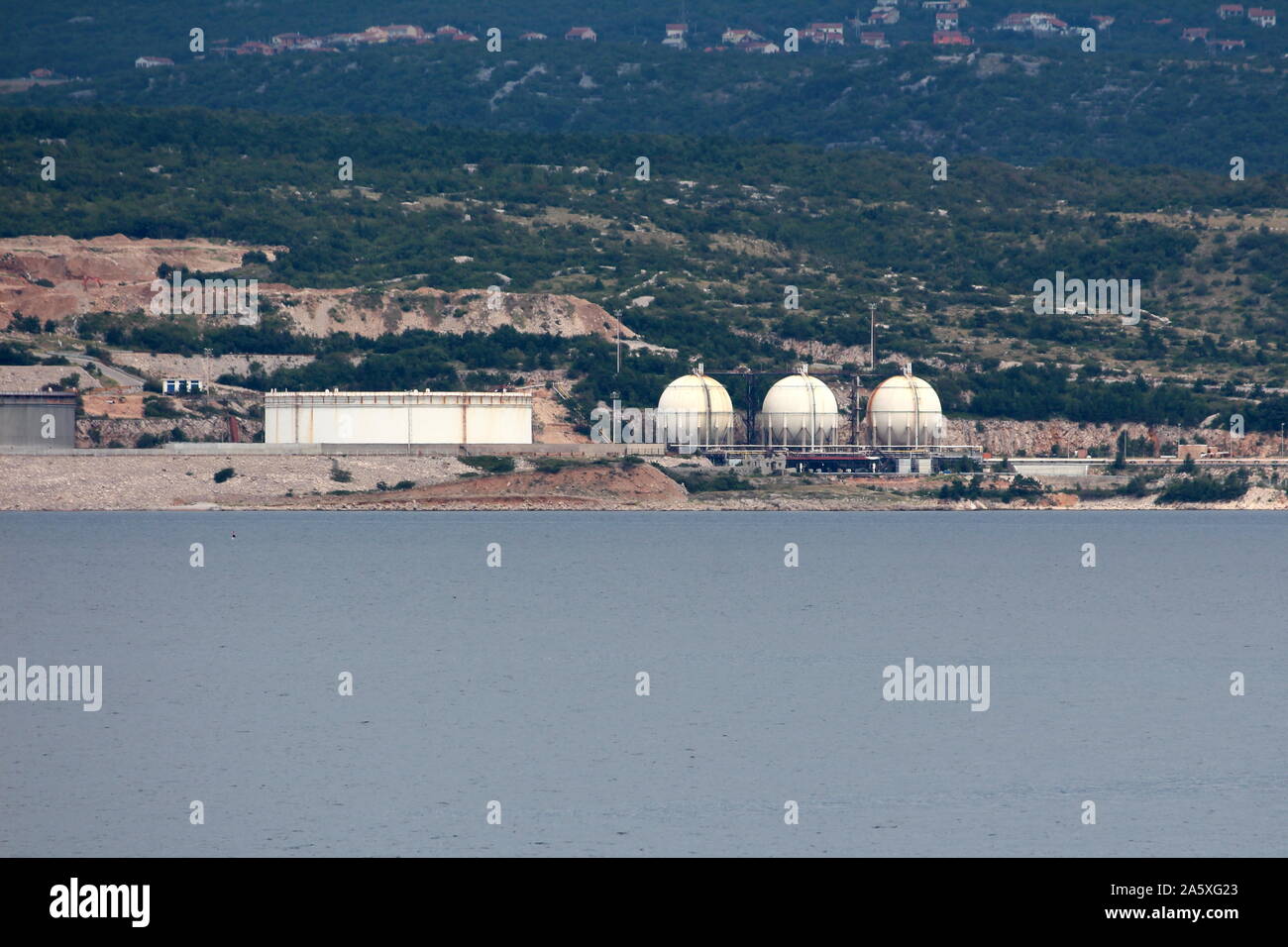 Large white oil refinery tank next to three dome shaped storage tanks ...