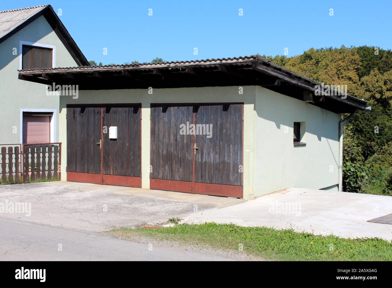 Light green outdoor garage with two wooden dilapidated doors on edge of ...