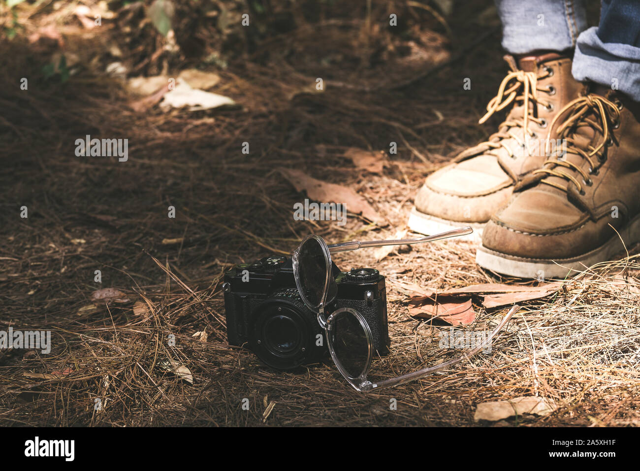 Closeup image of a man wearing boots with camera and sunglasses on the ...