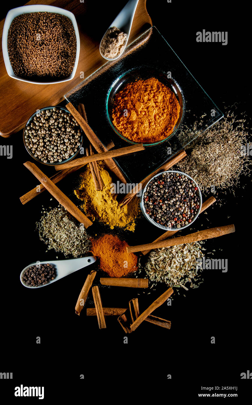Top view of a black table with lots of spices on top, cinnamon twigs ...
