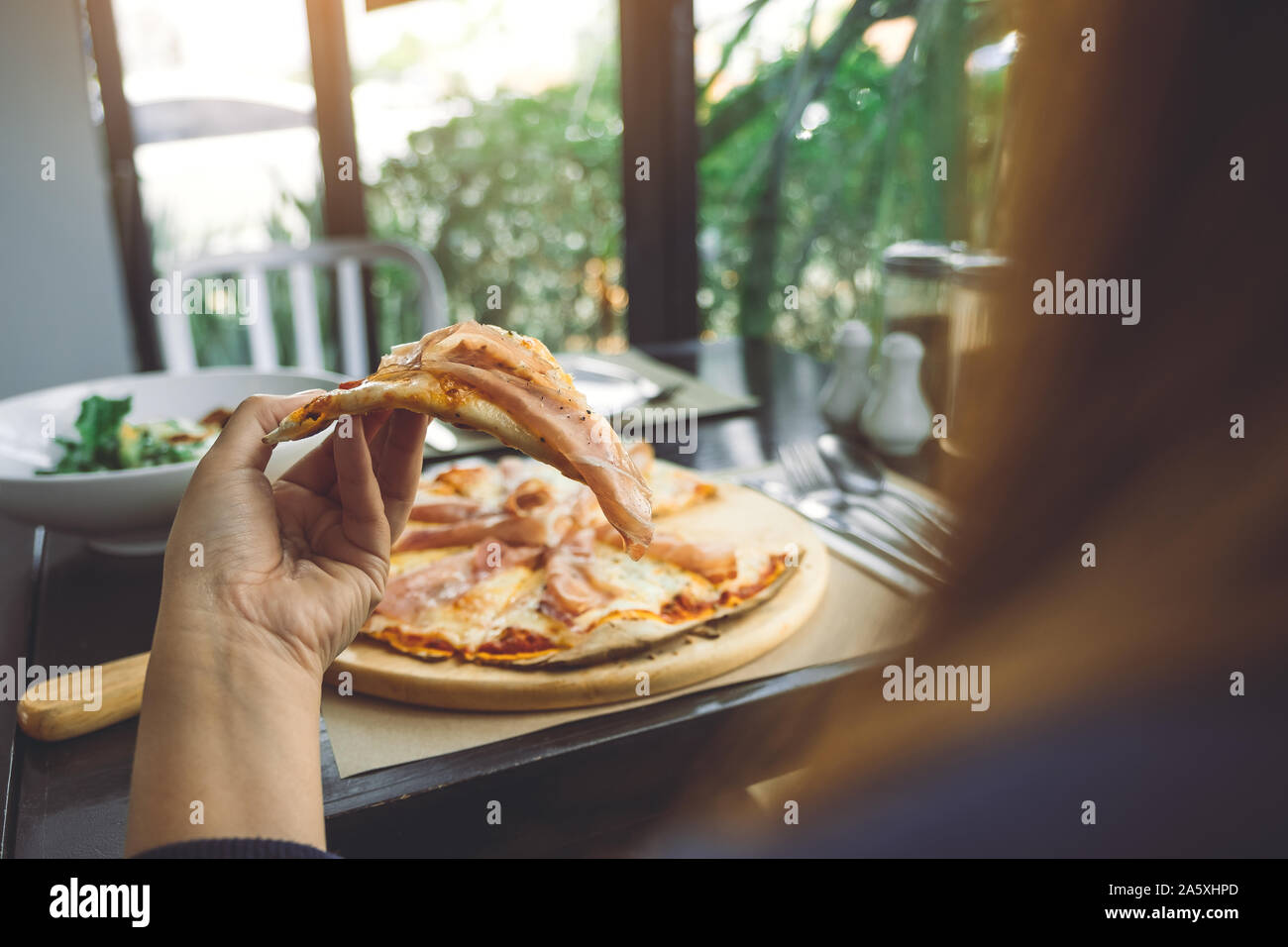 Closeup image of a woman picking a piece of Parma ham pizza up to eat ...