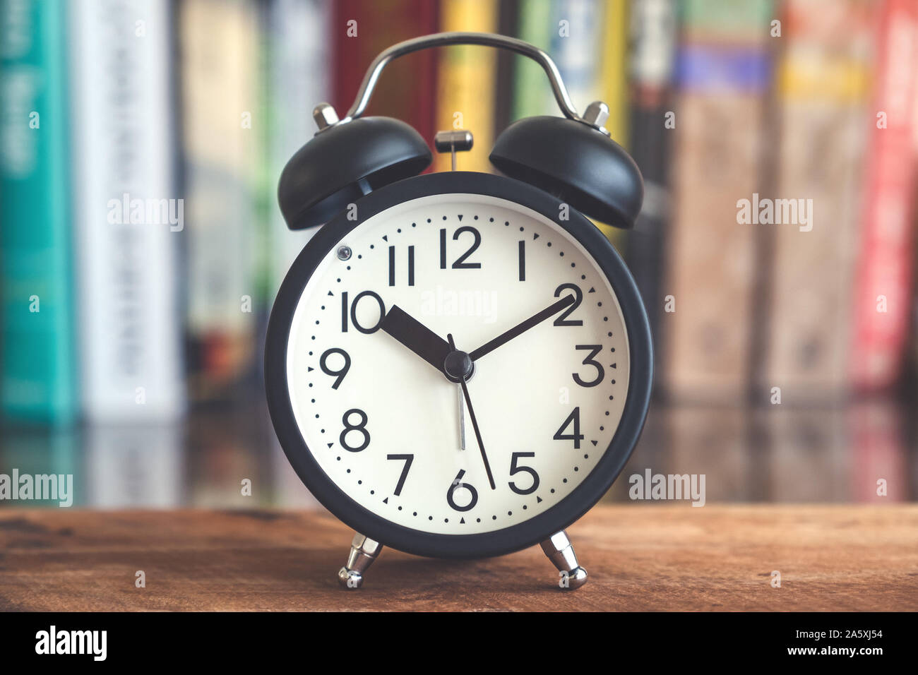 Closeup image of a black alarm clock on wooden table with blur ...
