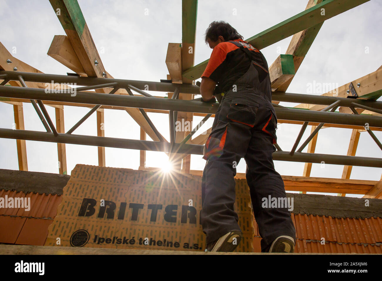 Man working on roof construction of building Stock Photo - Alamy