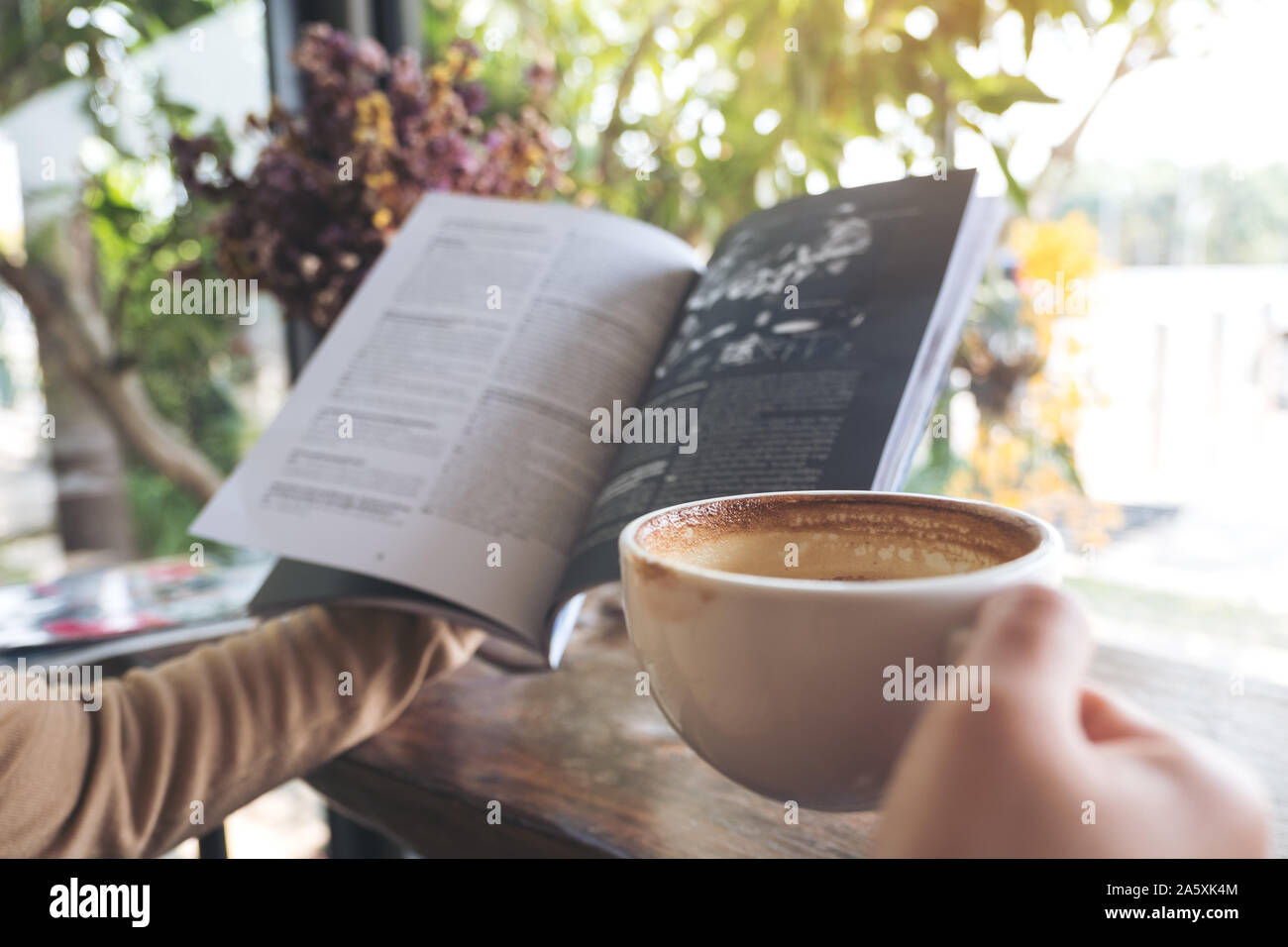 Closeup image of a woman reading book and drinking coffee in cafe Stock ...