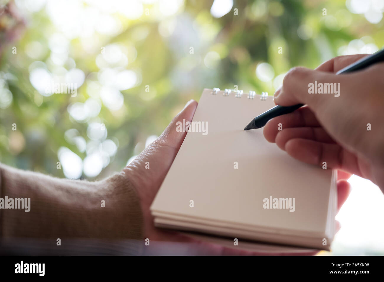 Closeup image of hands holding and writing down on a blank notebook ...