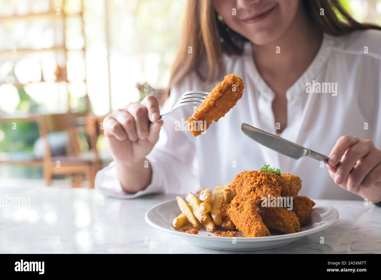 Closeup image of a beautiful asian woman enjoy eating french fries and ...