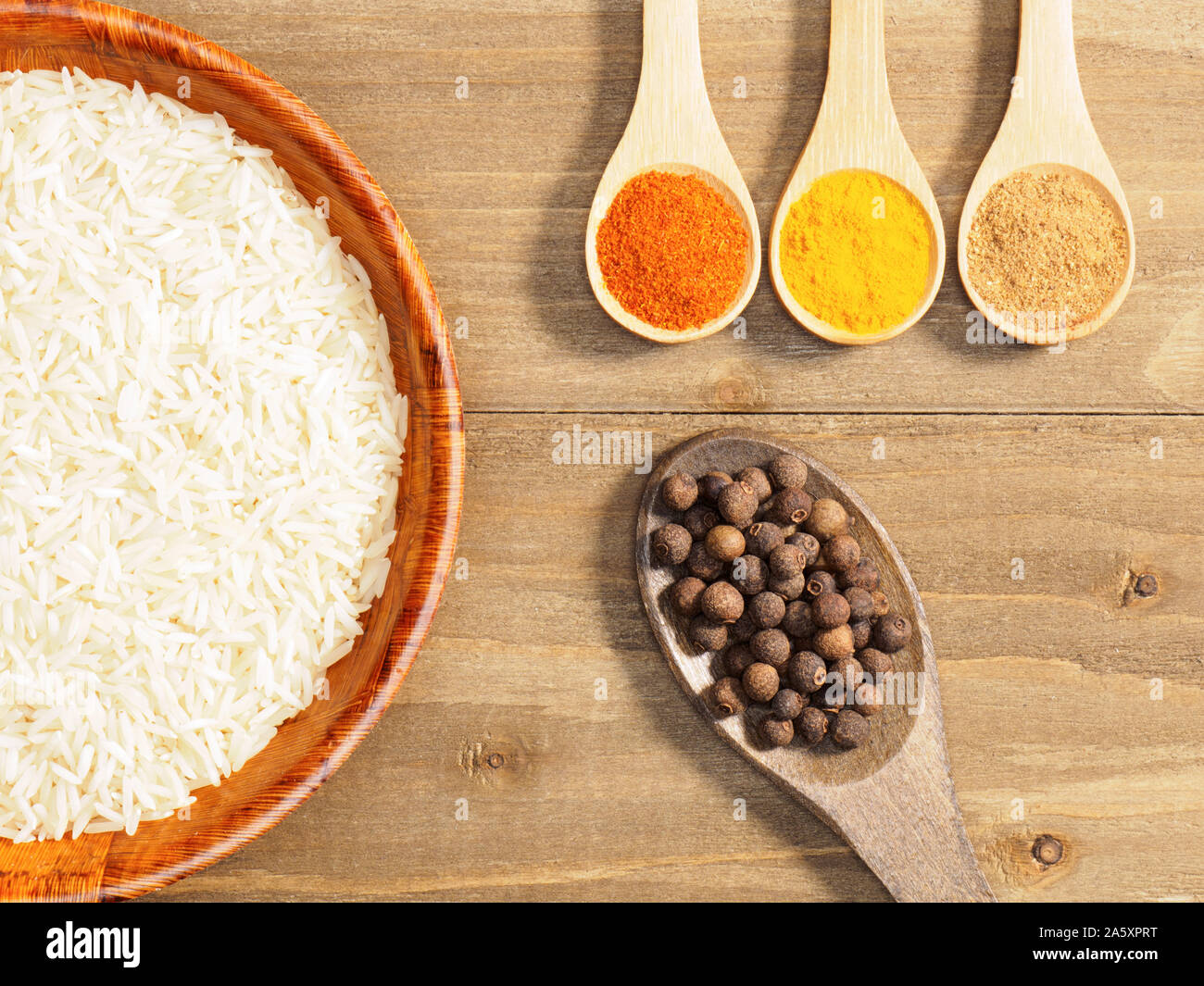 Rice, chili pepper, allspice, masala, turmeric on brown wooden ...