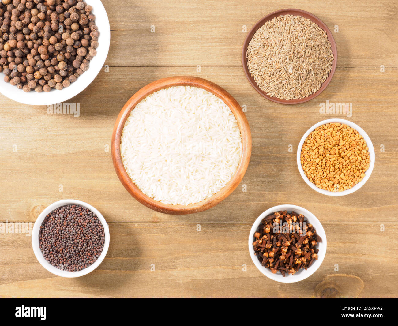 Rice, allspice, mustard seeds, fenugreek, cumin, cloves on brown wooden ...
