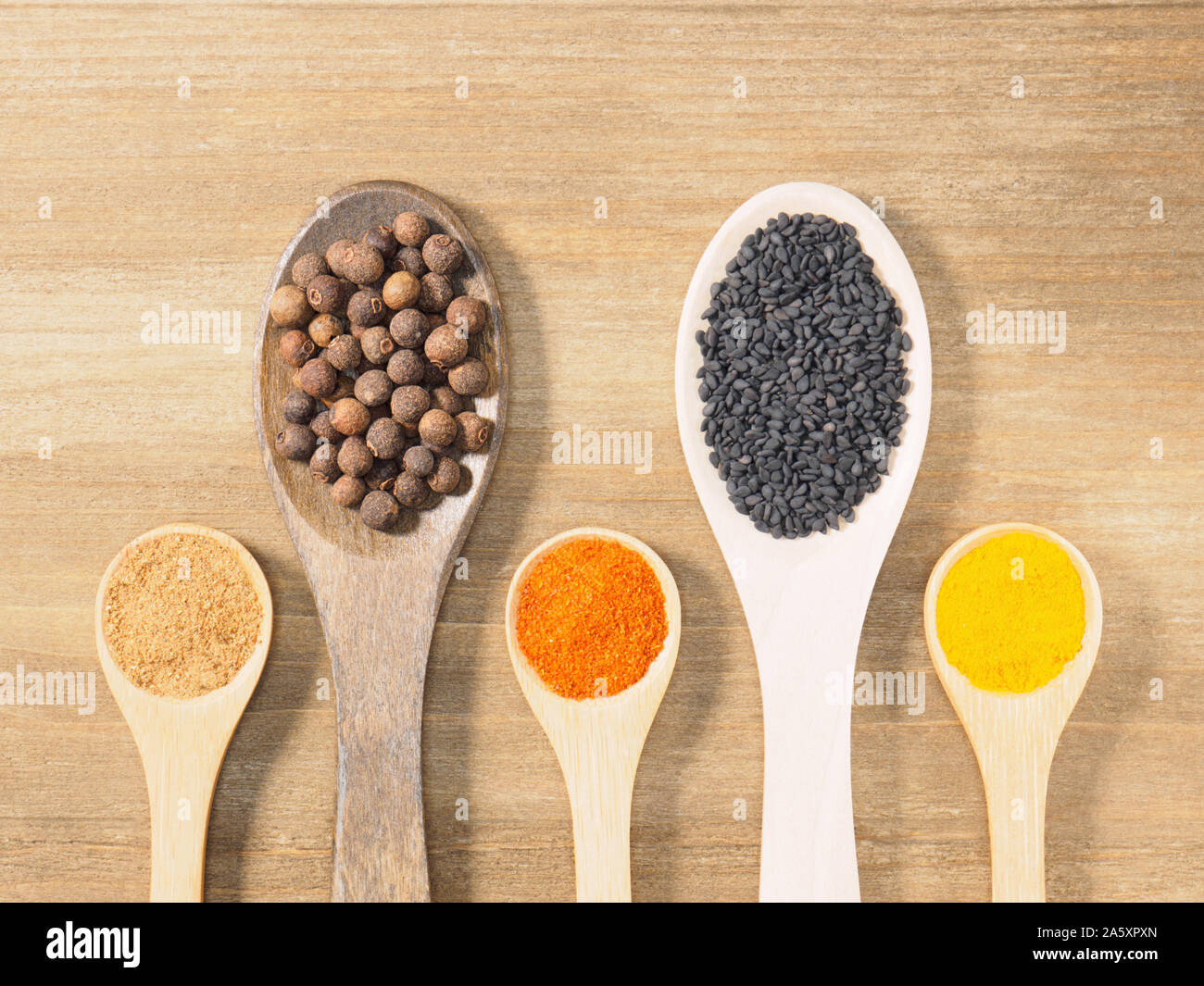Allspice, black cumin, turmeric, masala, chili pepper on brown wooden ...