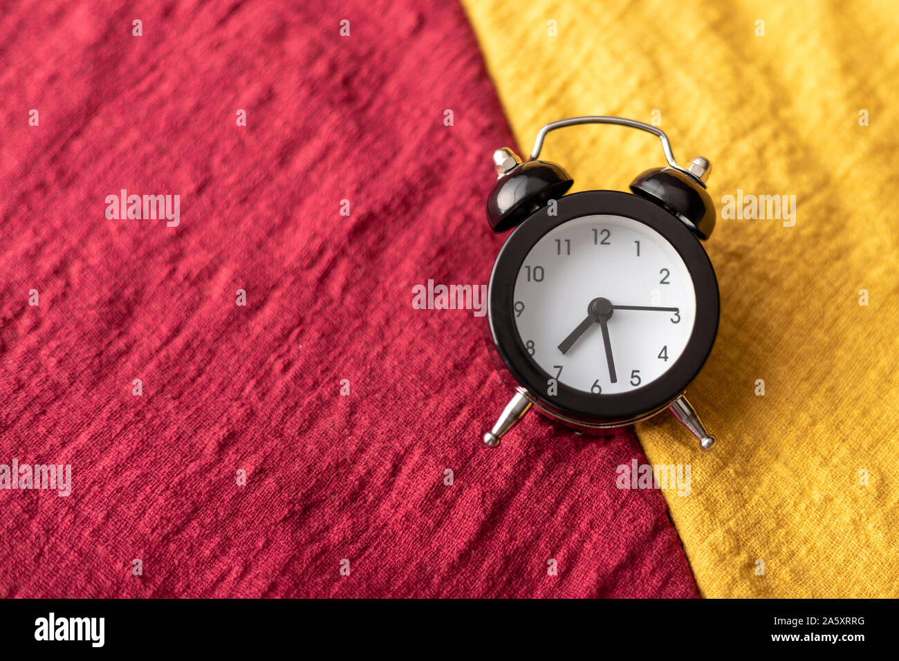 The black clock place on the red and yellow fabric. Abstract background ...